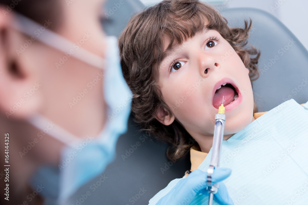 partial view of dentist giving injection on anesthesia to patient in ...