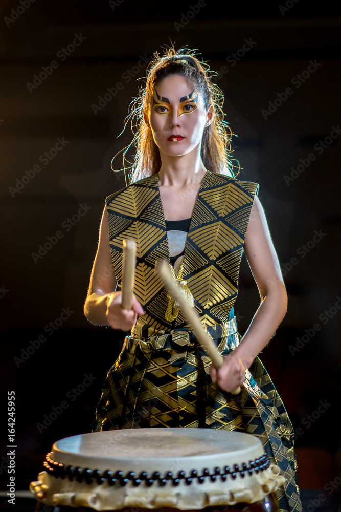 beautiful asian drummer girl with drumsticks, studio shot on a dark ...