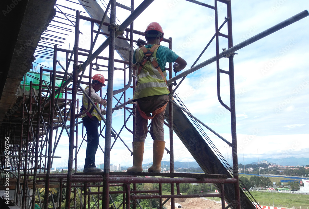 Construction workers wearing safety harness and adequate safety gear ...