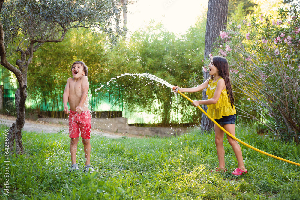 girl spraying boy with water hose Stock Photo | Adobe Stock