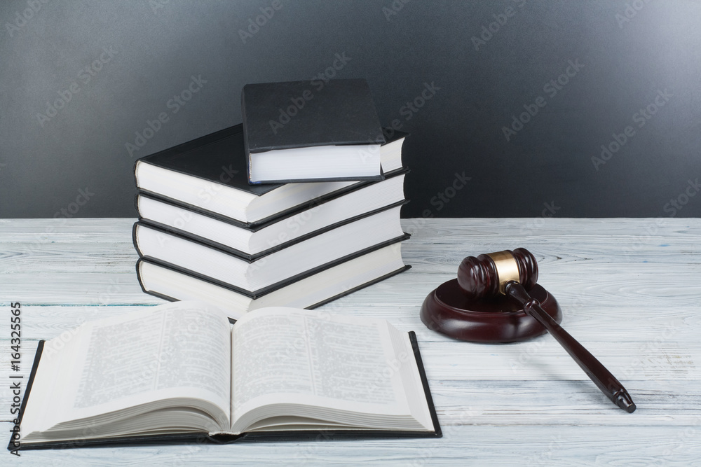 Law concept - Open law book with a wooden judges gavel on table in a ...