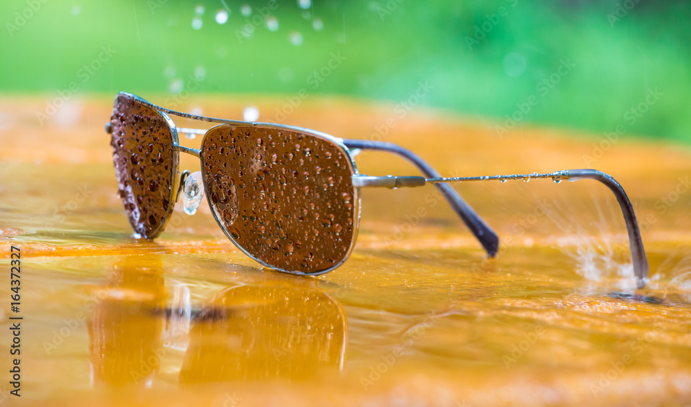 In heavy rain sunglasses lie on a table Stock Photo | Adobe Stock