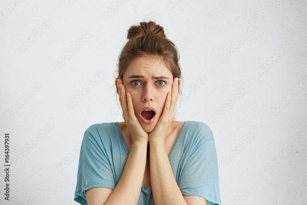 Horrified woman with attractive appearance looking scared keeping her ...