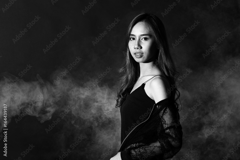 low key portrait of slim healthy woman in black background with fog smoke and light from back ...