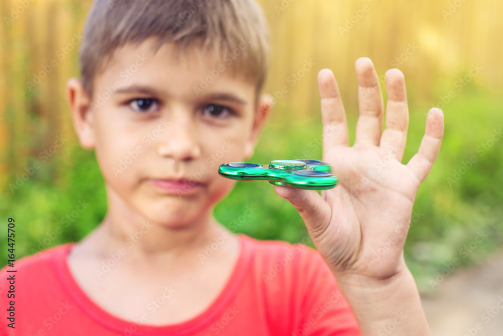 A boy plays with spinner twisting it in his hand on outdoors. Trends in ...