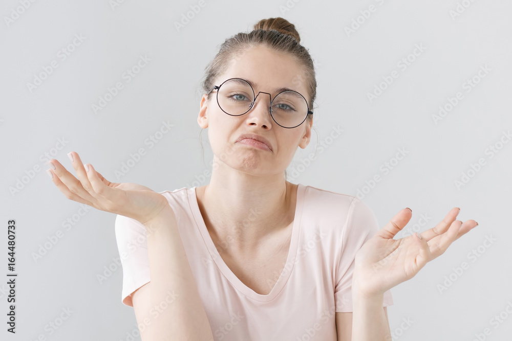 Indoor photo of confused young female wearing trendy hipster eyeglasses ...