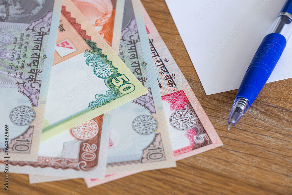 Nepal rupee money with a shett of paper and a pen for calculations ...