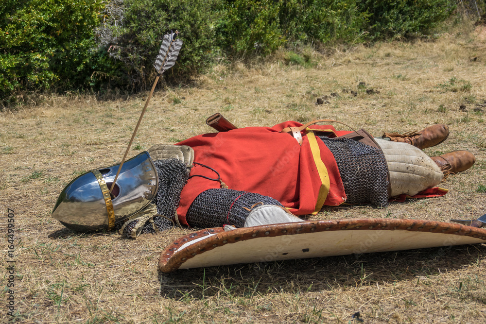 Medieval knight fallen in battle, with an arrow piercing his helmet and ...