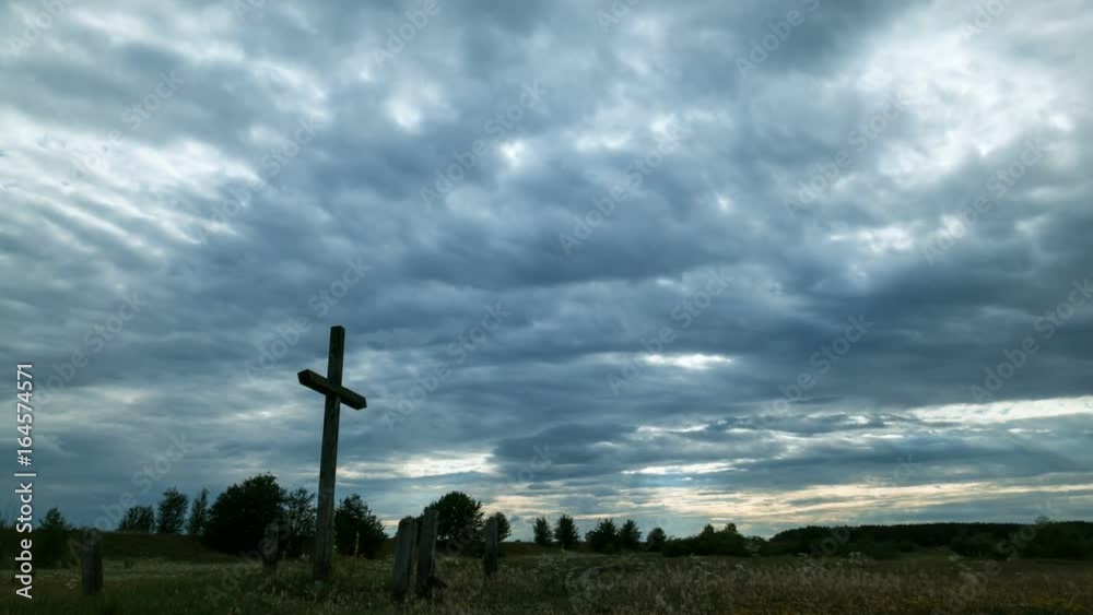 Wooden cross in the field above the dramatic sky with clouds. Time ...