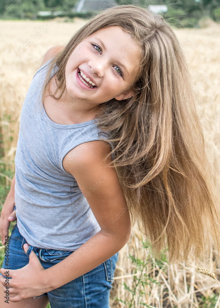 sexy little girl playing with her long hair posing in wheat field at a ...