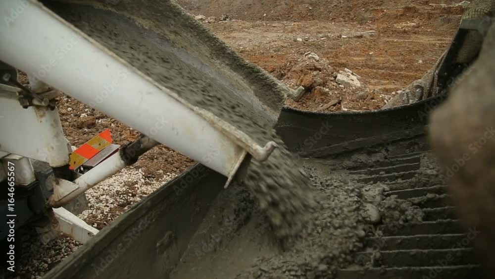 Pouring concrete mix from cement mixer on concreting formwork. Finished ...