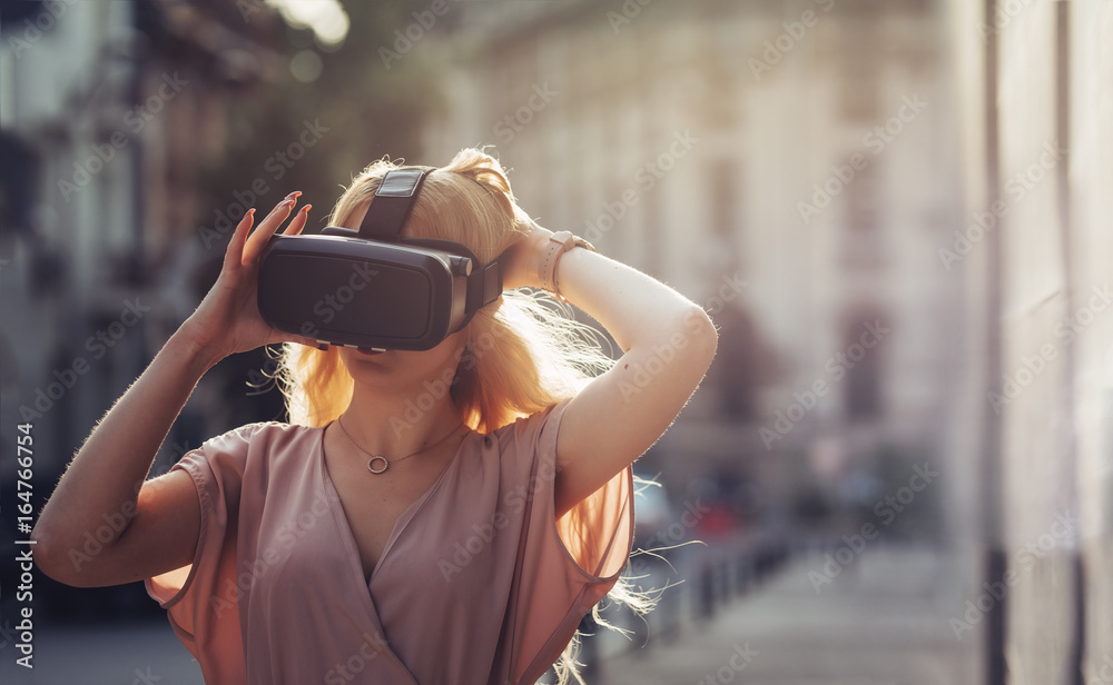 Blonde girl using cool VR set to experience living in fantasy computer ...