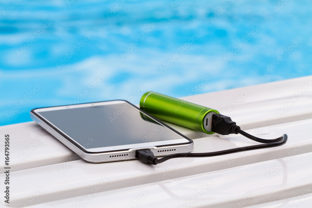 Smartphone connected to the green portable battery charger through USB ...