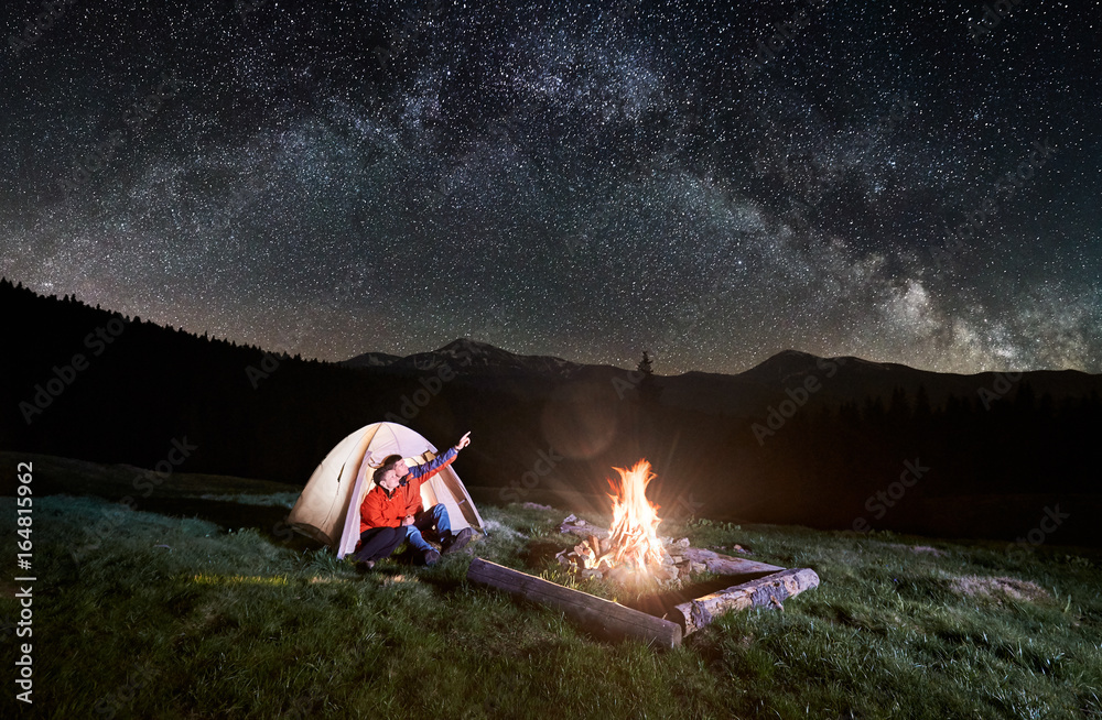 Night camping in the mountains. Couple tourists sitting in the ...