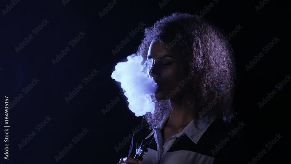 African american girl smokes an vaping in an empty room. Black ...