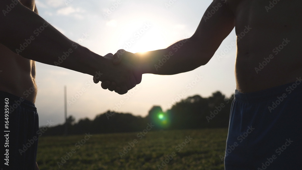 Friendly handshake of two unrecognizable muscular white men with sun ...