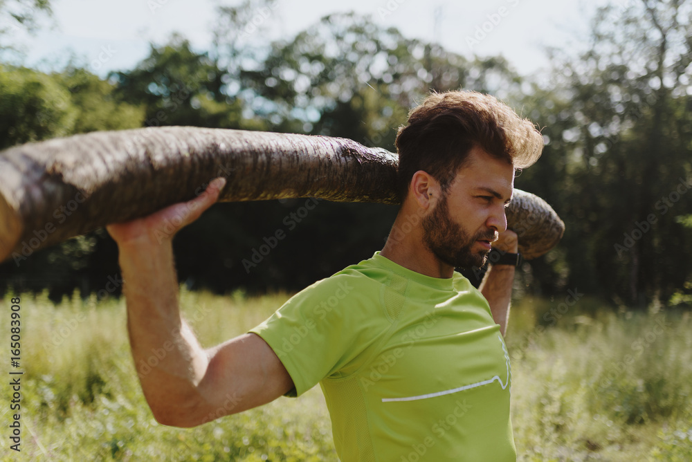 Young man lifting wooden log outdoors Stock Photo | Adobe Stock