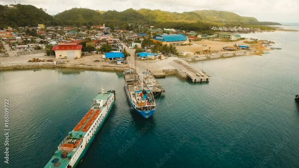 Cargo and passenger port with barges and cargo ships on tropical island ...
