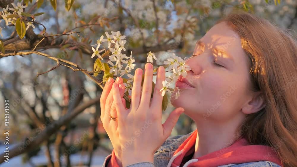Young woman smelling flowers in the orchard. Beauty girl outdoor ...