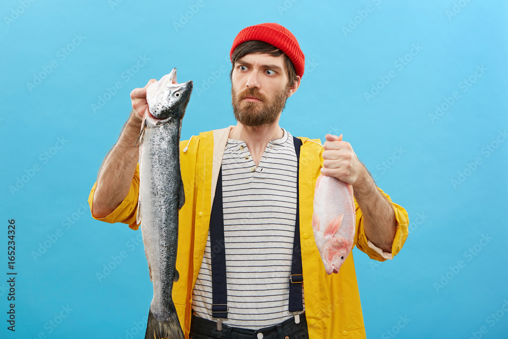 Serious man with blue eyes and thick beard wearing red hat and yellow ...