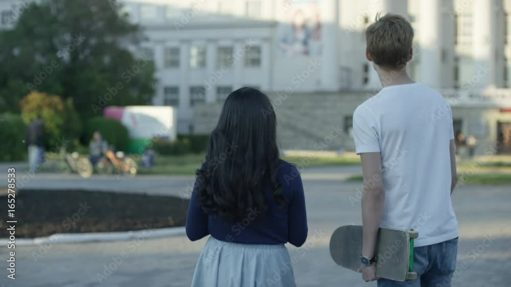 Rear view portrait of two students carrying walking and look at the ...