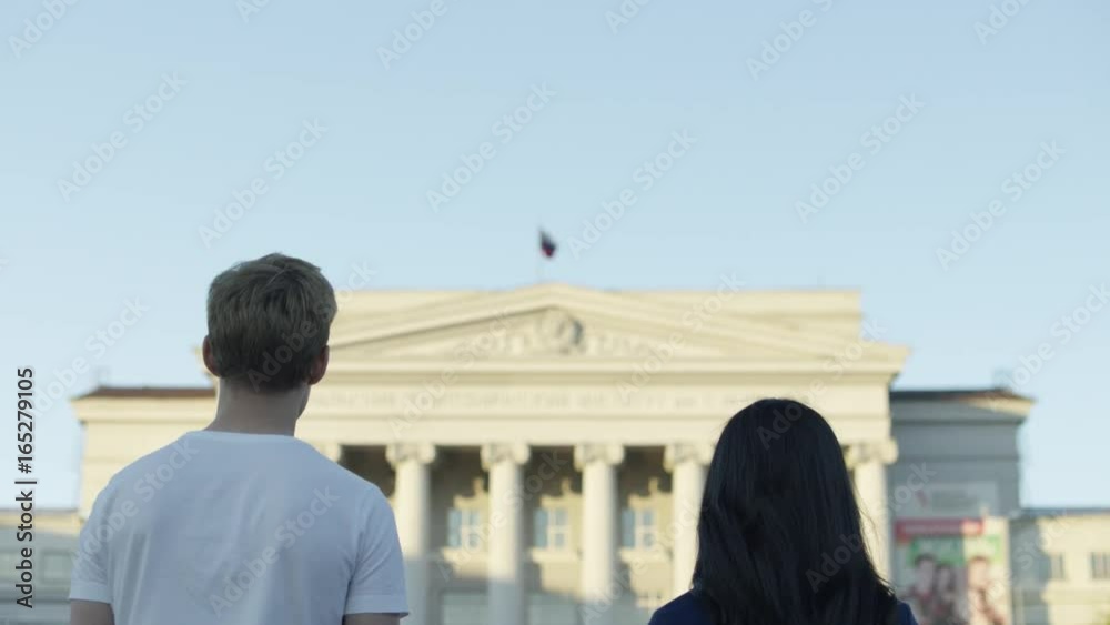 Rear view portrait of two students carrying walking and look at the ...