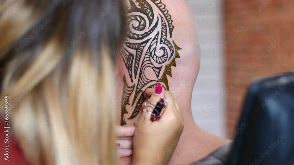 A girl, tattoo master, mehendi artist makes drawing of henna tattoo on ...