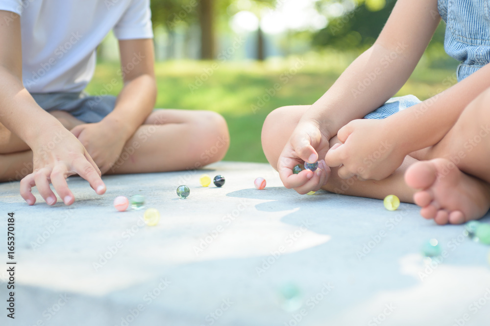 Kids playing marbles game outside Stock Photo | Adobe Stock