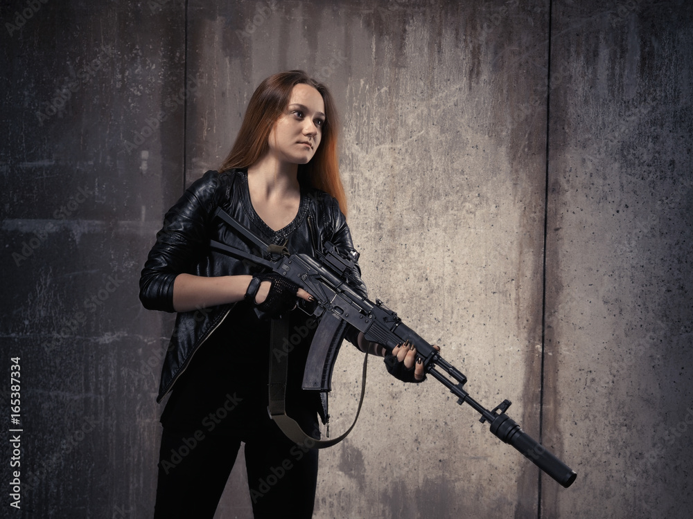 young girl in a black leather jacket with a gun machine. Luxurious long ...