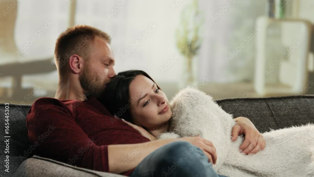 Young sweet couple cuddling on couch and talking Stock Video | Adobe Stock