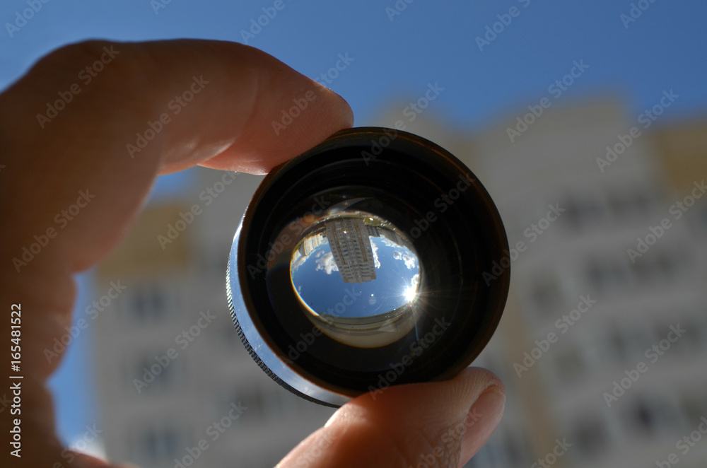 High building is reflected in the magnifying glass. Blue sky background ...