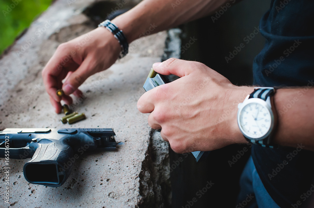 Man charges clip of pistol with bullets. Photo hands of paramilitary ...