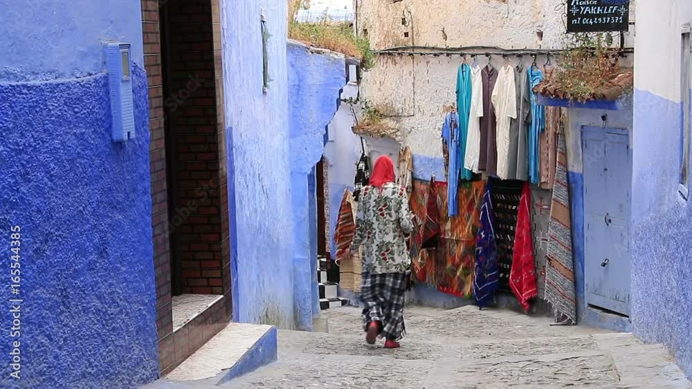 Walking people with traditional Arabic clothes in blue town Chefchaouen ...