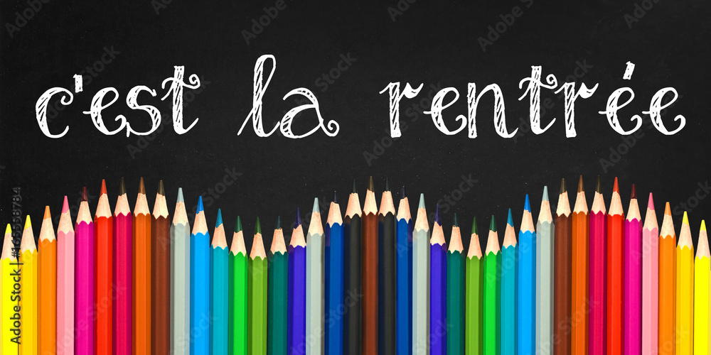 C'est la rentrée écrit sur sur une ardoise, crayons de couleurs en bois ...