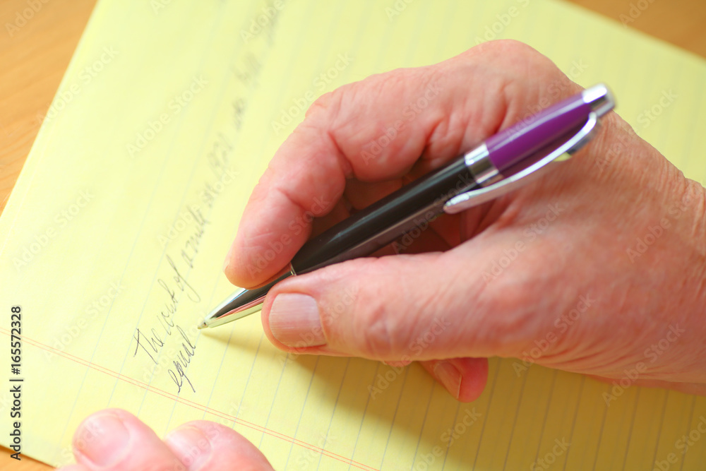Older man writes in cursive on a ruled yellow pad of paper Stock Photo ...