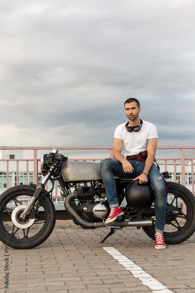 Handsome rider guy with a beard and mustache sit on classic style biker ...