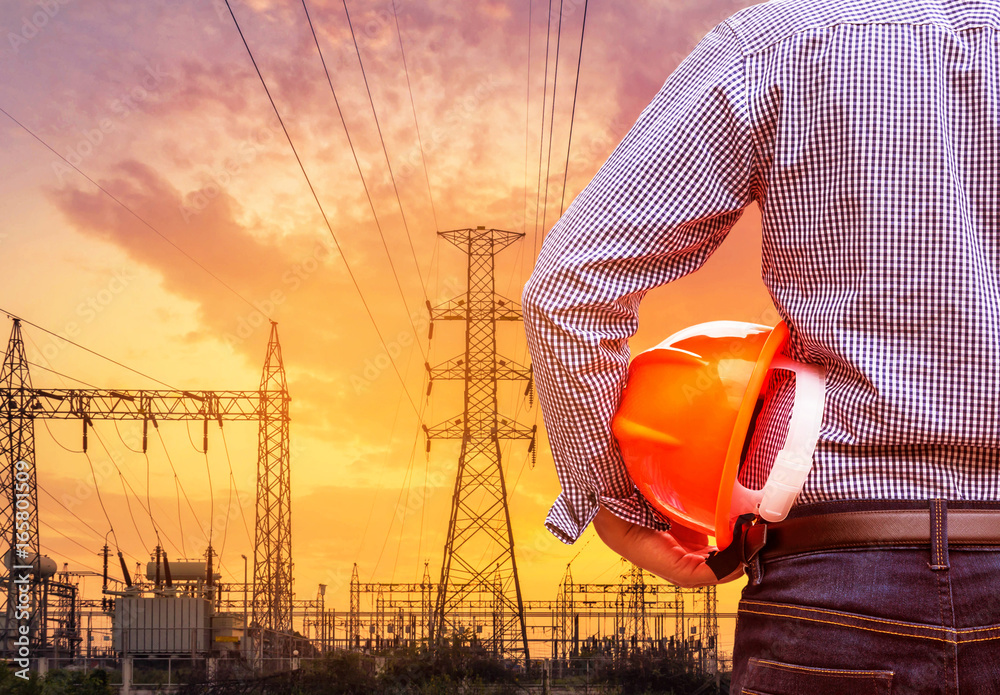 engineer holding yellow safety helmet with high voltage electric pylon ...