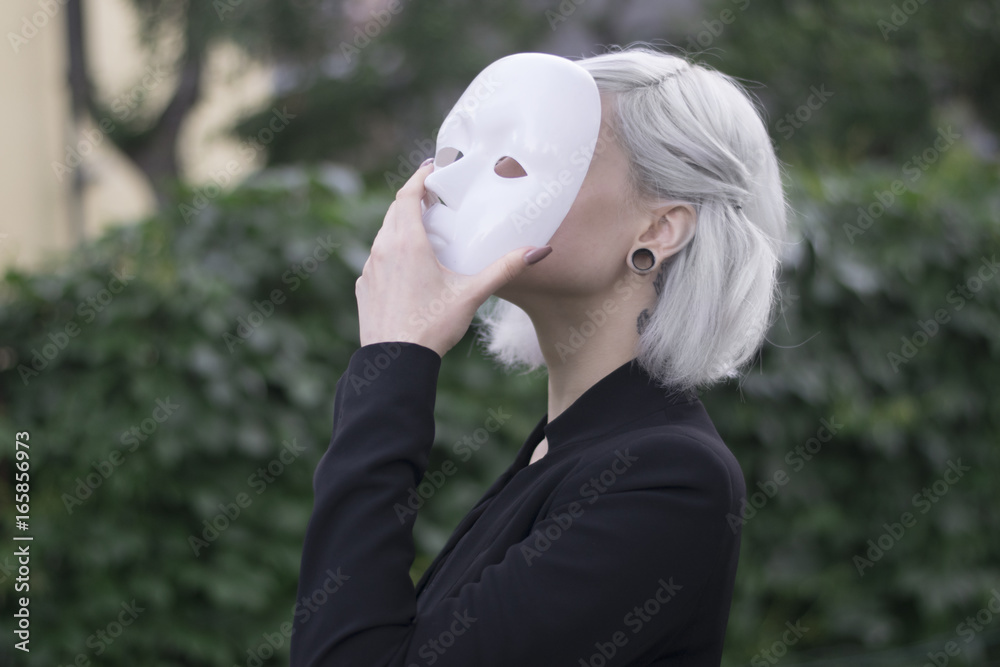 Young blond woman taking off a mask. Pretending to be someone else ...