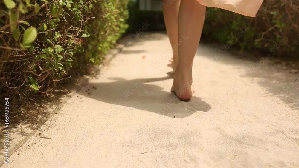 Back view of woman's feet going to spa room bungalow on exotical ...