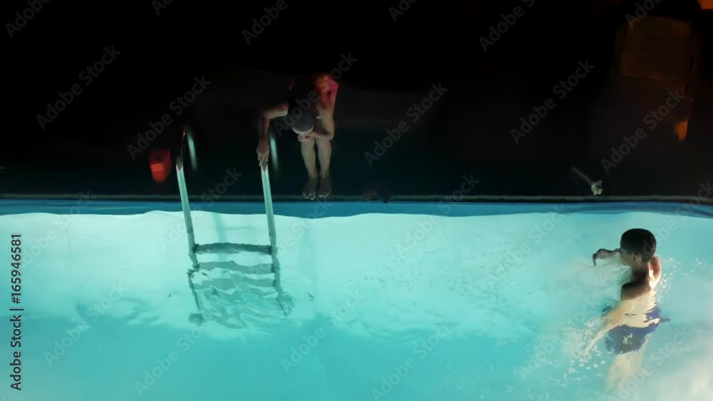 Boy and girl bathe in the pool kids at night. Children amusement swim ...