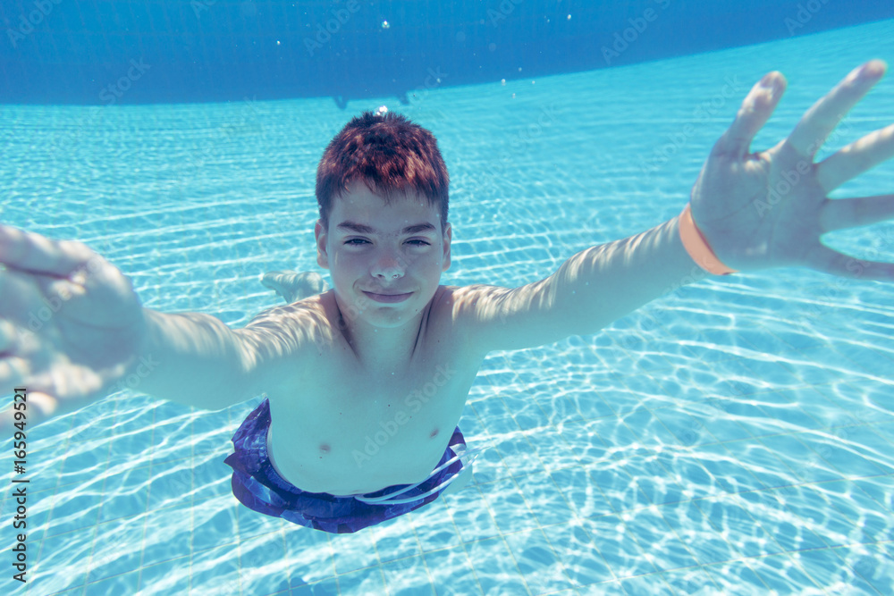 Teenage boy, diving underwater at spa resort swimming pool. Stock Photo | Adobe Stock