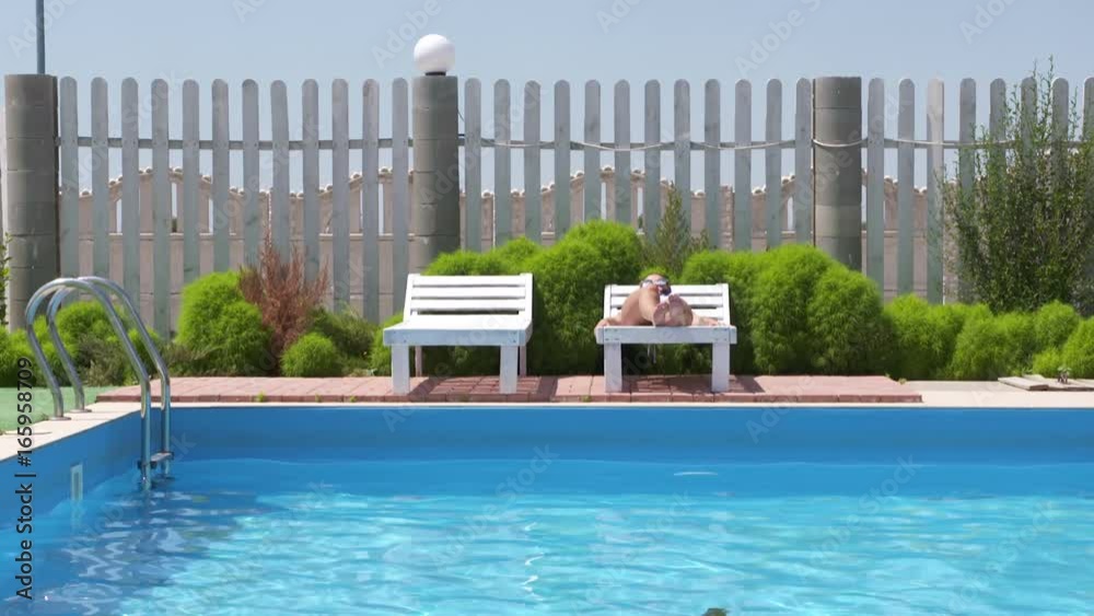Young girl in white bikini relaxing by the side of outdoor swimming ...