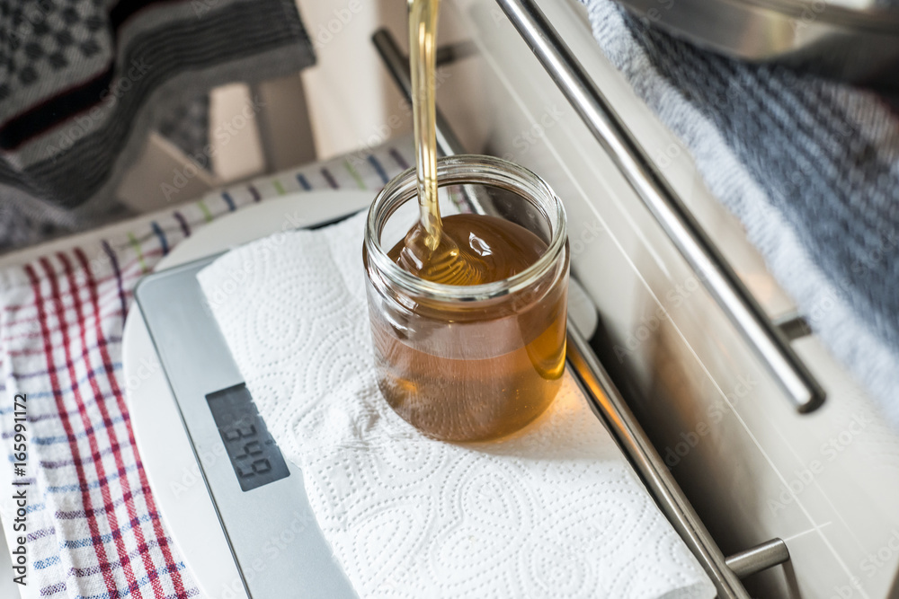Beekeeper filling up the fresh golden new honey into glass jars on a ...