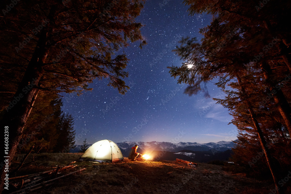 Male tourist have a rest in his camp near the forest at night. Man ...