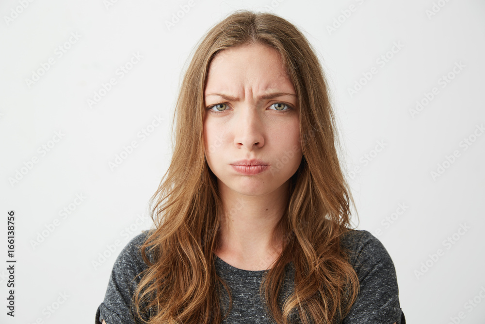Portrait of young pretty offended girl with funny face looking at ...