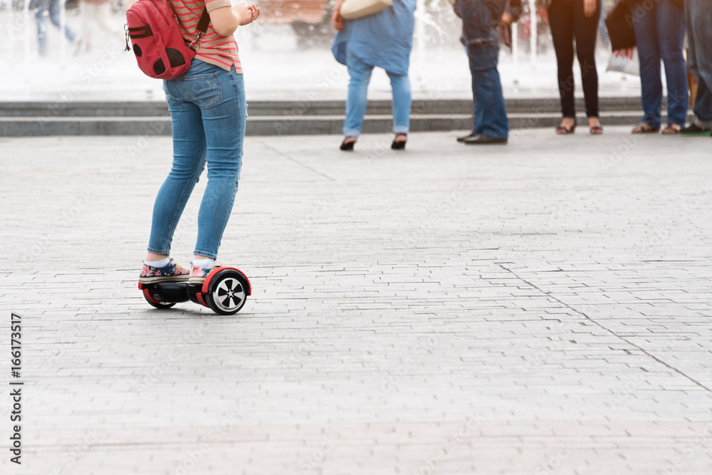 Young woman riding a hoverboard on the city square. New movement and ...