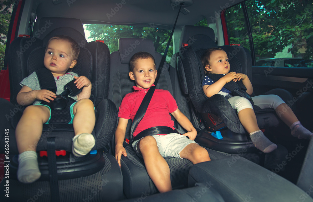 Three children in car safety seat - family, transport, safety, road ...