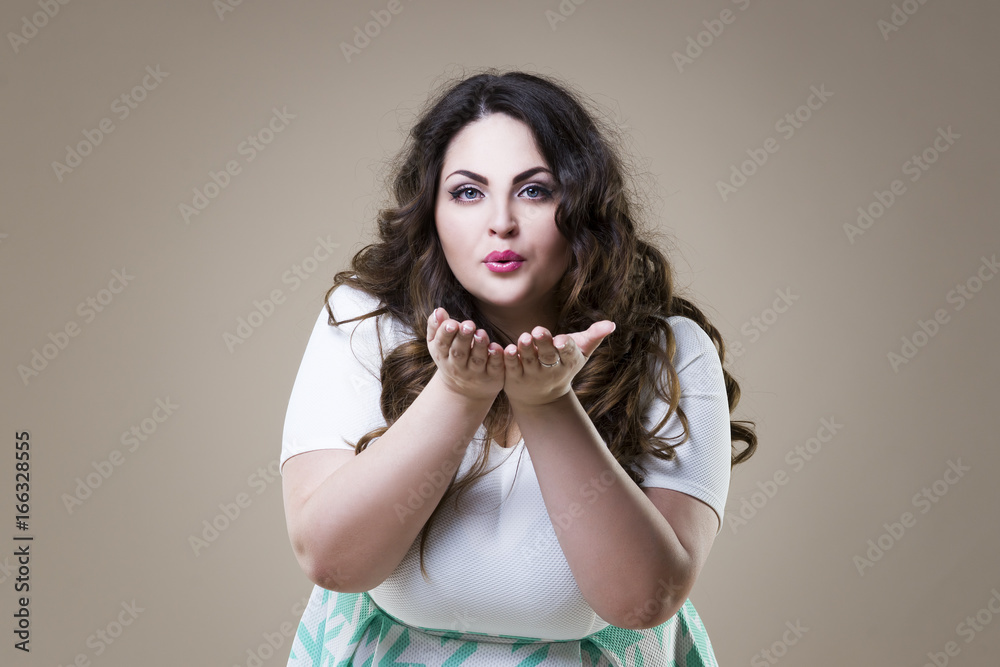 Plus size fashion model sends air kiss, fat woman on beige background ...