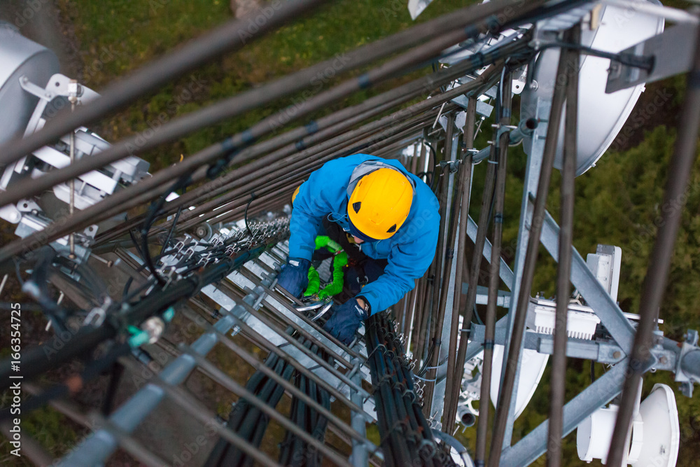 Working at heights, technician climbs up on a communications tower ...