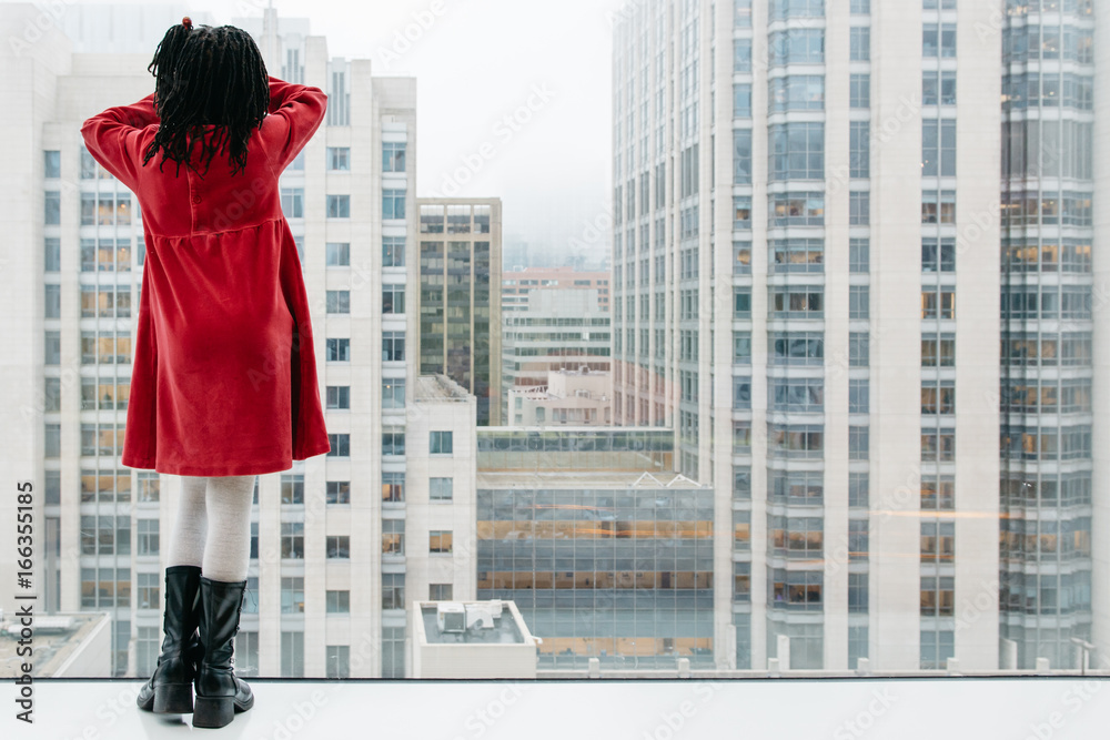 Black girl in red dress looking out of an high-rise building Stock ...